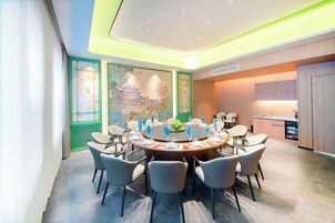 Uma zona de refeições moderna com uma mesa redonda, cadeiras e uma cozinha ao fundo.