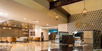Um hall de hotel com balcão de recepção, área de estar e lustres modernos.