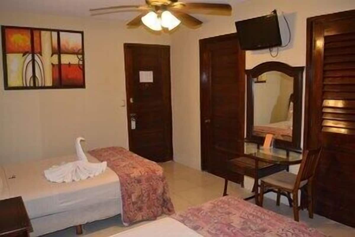 Quarto com uma cama, escrivaninha, cadeira, televisão e um quadro na parede.
