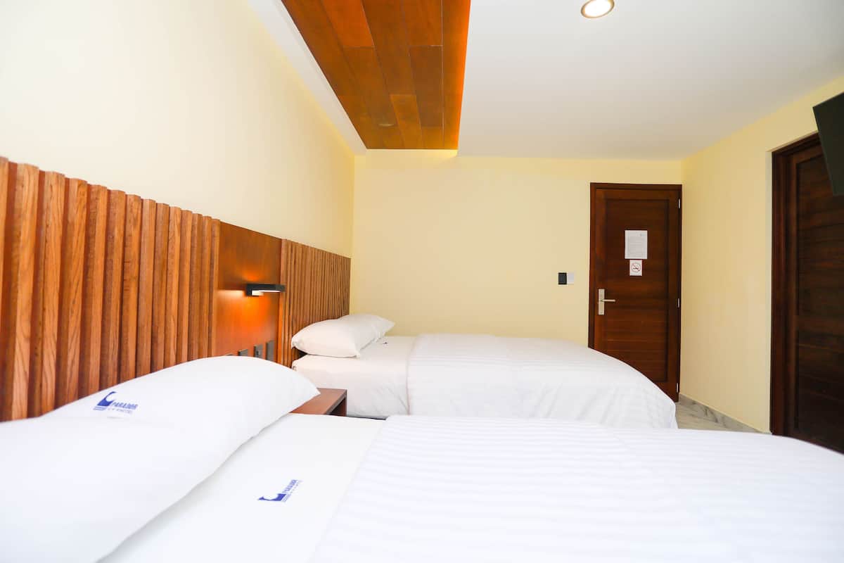 Quarto de hotel com duas camas, cabeceira de madeira e uma porta com uma placa.