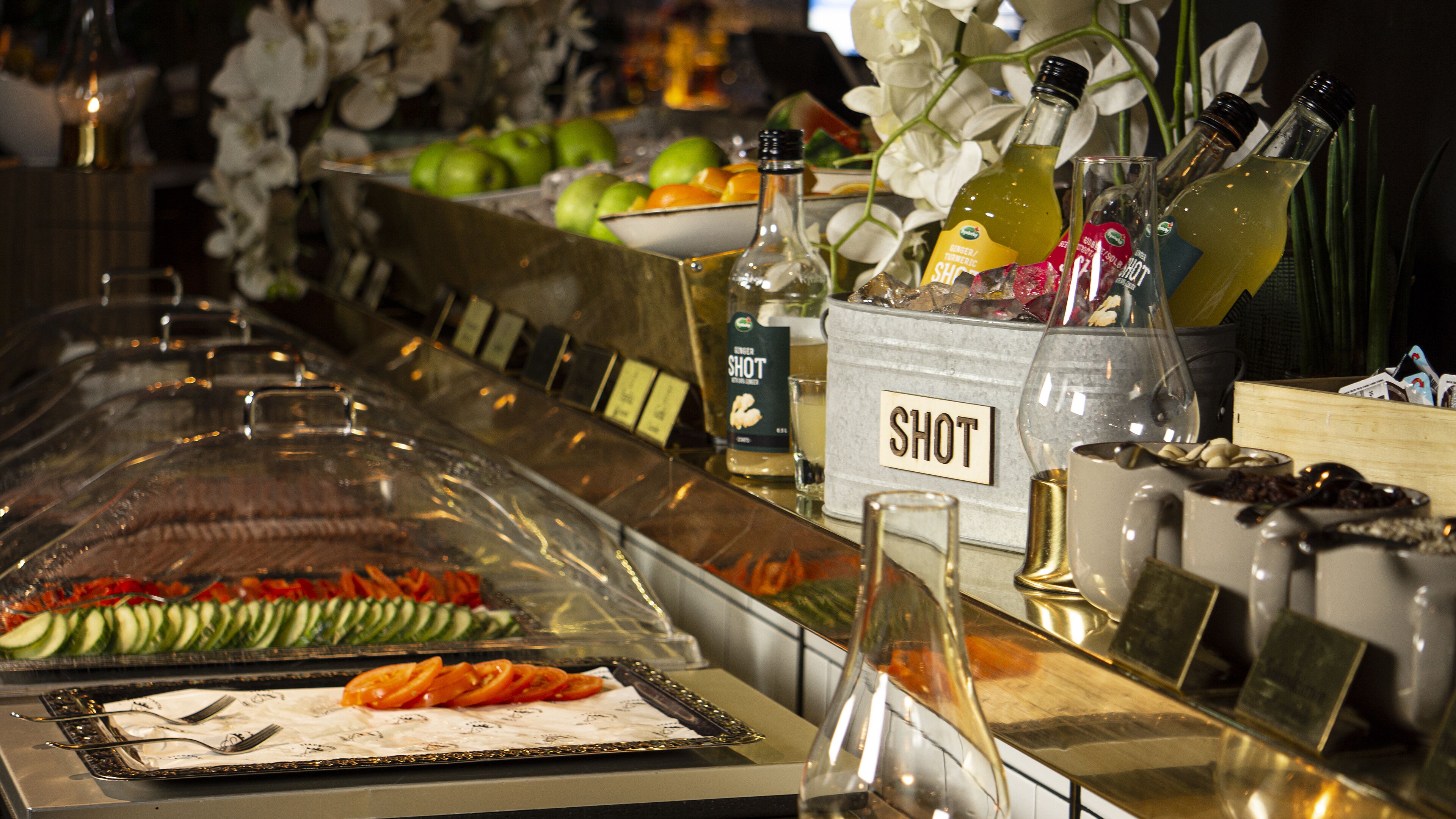 Buffet com diversos alimentos e um bar de shots com garrafas.