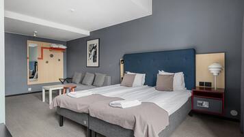 Quarto de hotel moderno com uma cama grande, uma mesa de cabeceira, um criado-mudo com abajur e um espelho na parede.