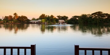 Um lago calmo com uma fonte no centro, rodeado por árvores e edifícios.