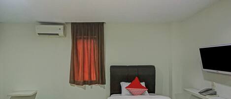 Quarto de hotel com duas camas, televisão na parede, aparelho de ar condicionado e janela com cortinas.