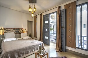 Quarto espaçoso com cama grande, vista para a varanda e um lustre moderno.