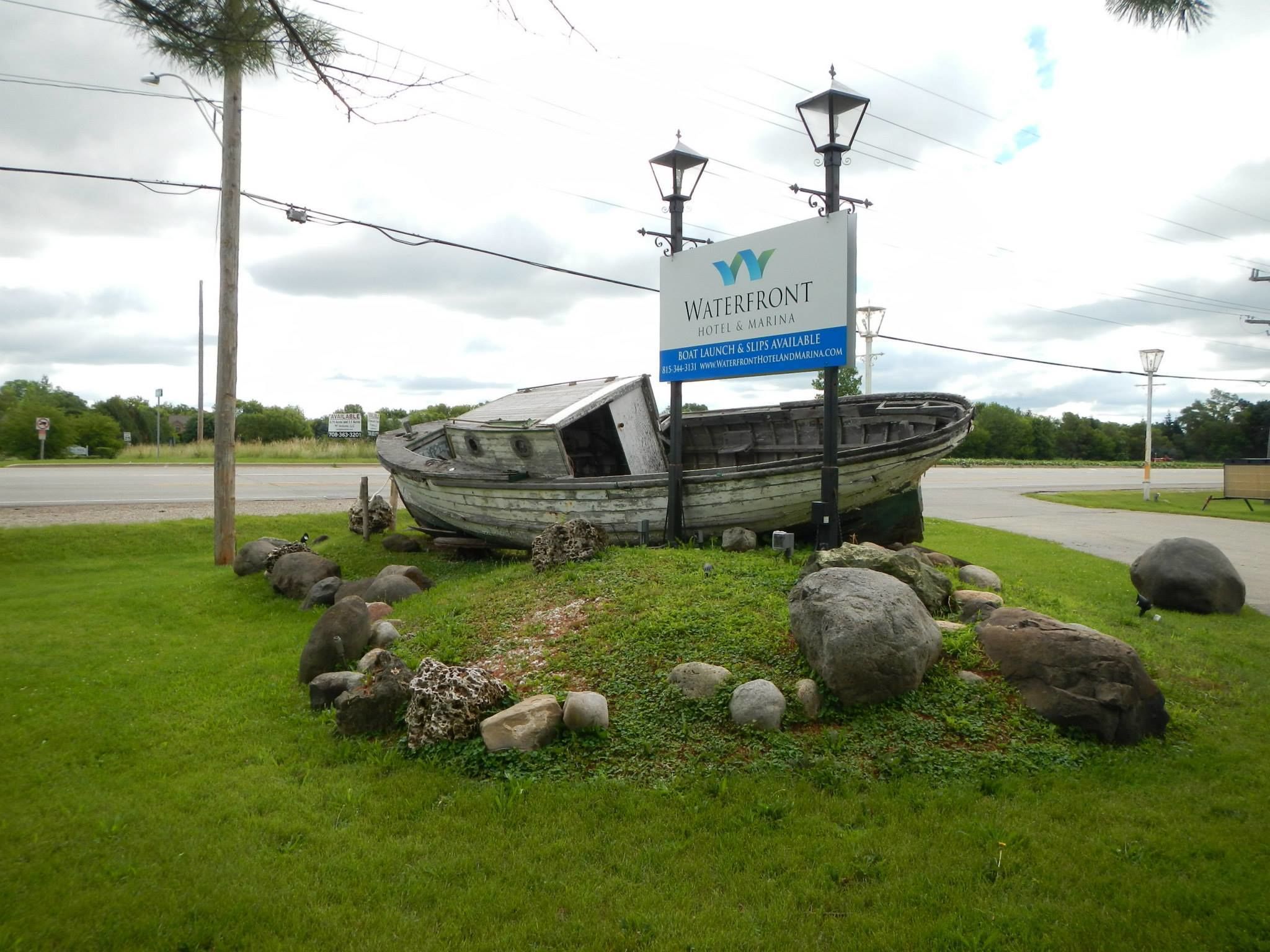 Um barco com uma placa indicando Waterfront Hotel & Marina, cercado por rochas e grama.