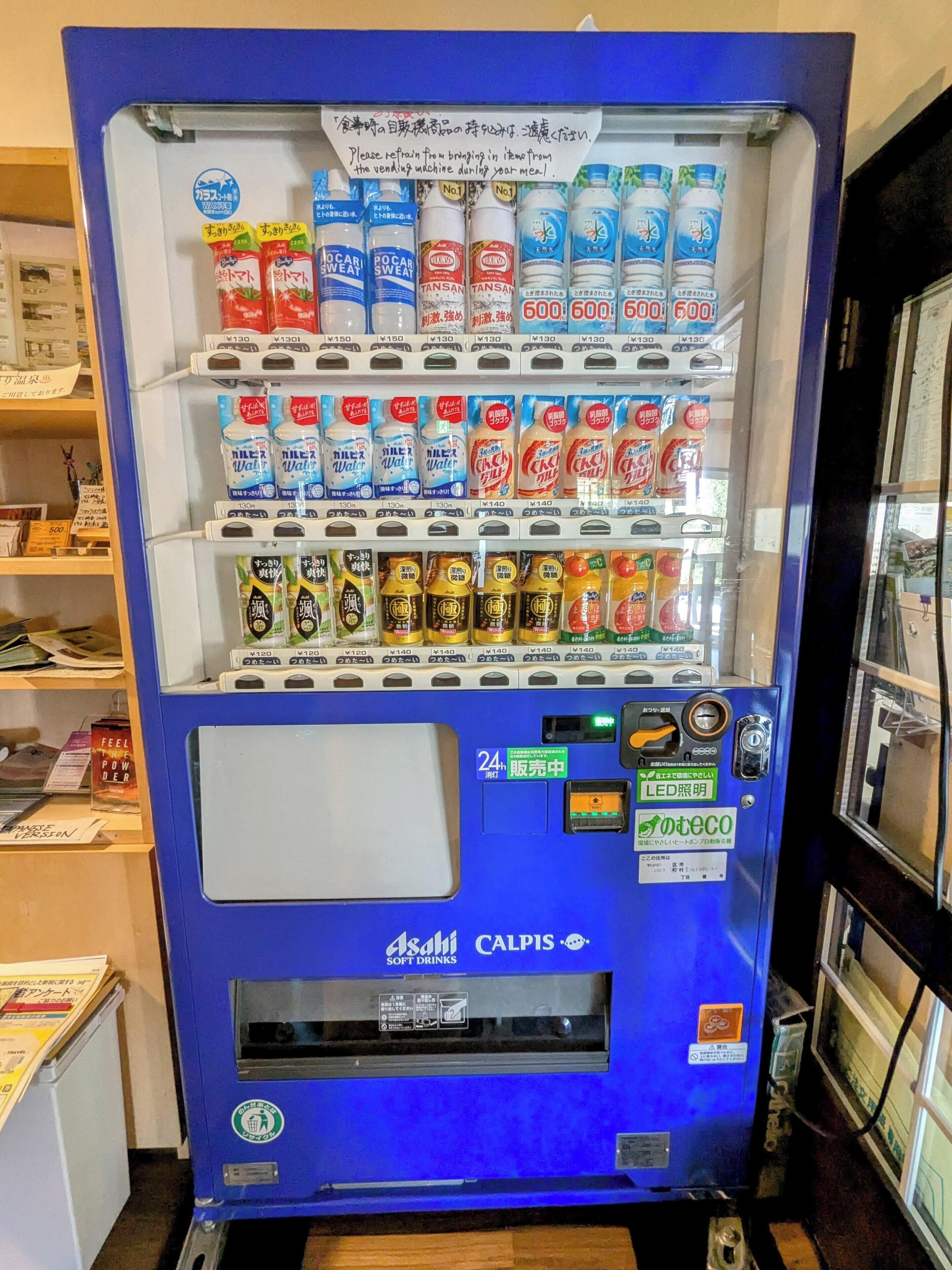 Máquina de vendas com diversas opções de bebidas, incluindo água, refrigerantes e lanches.