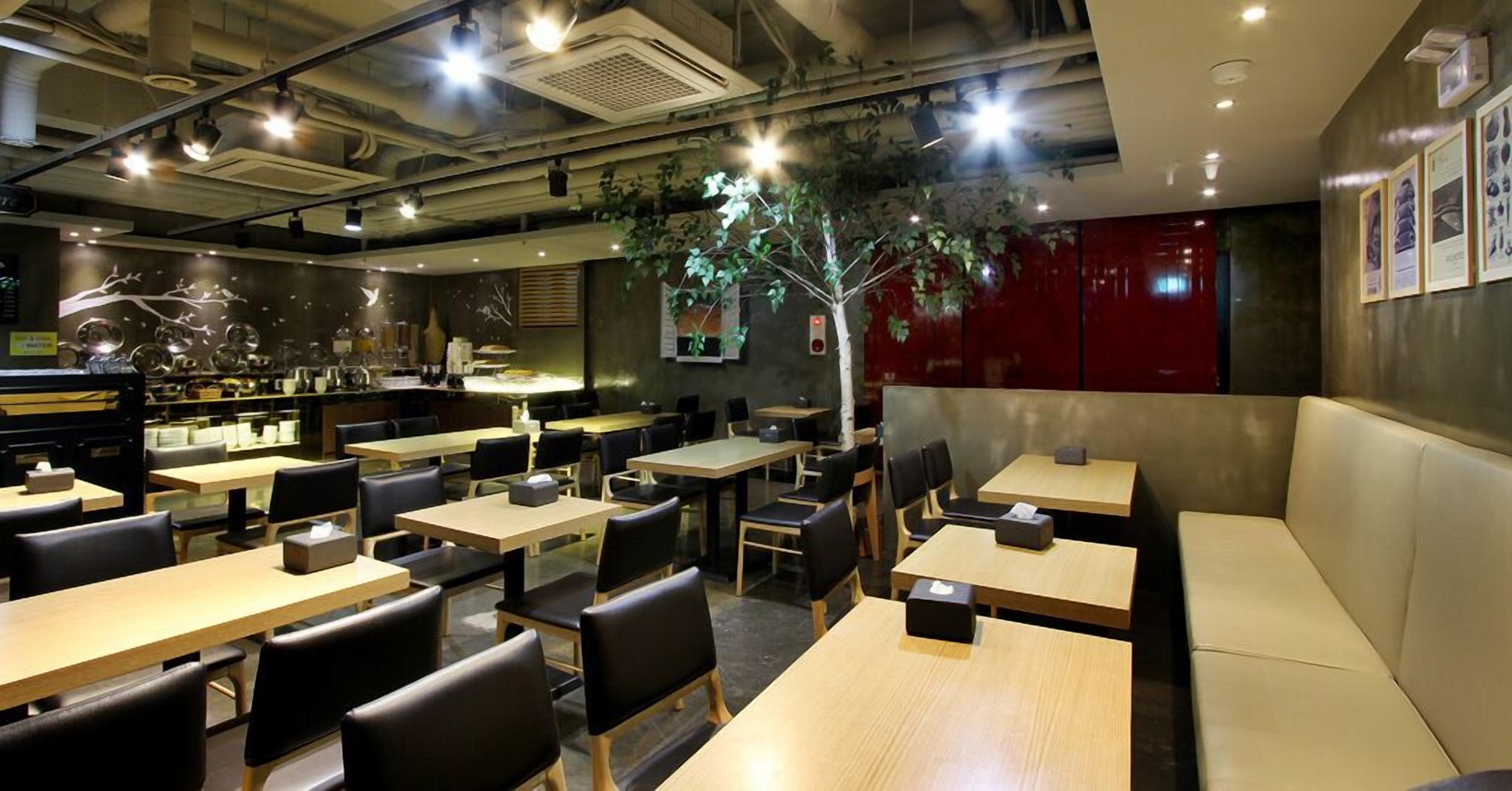 Restaurante com várias mesas e cadeiras, um espaço de bar e uma parede com quadros.