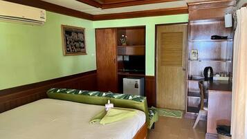 Quarto de hotel com cama, escrivaninha, guarda-roupa, televisão e banheiro.