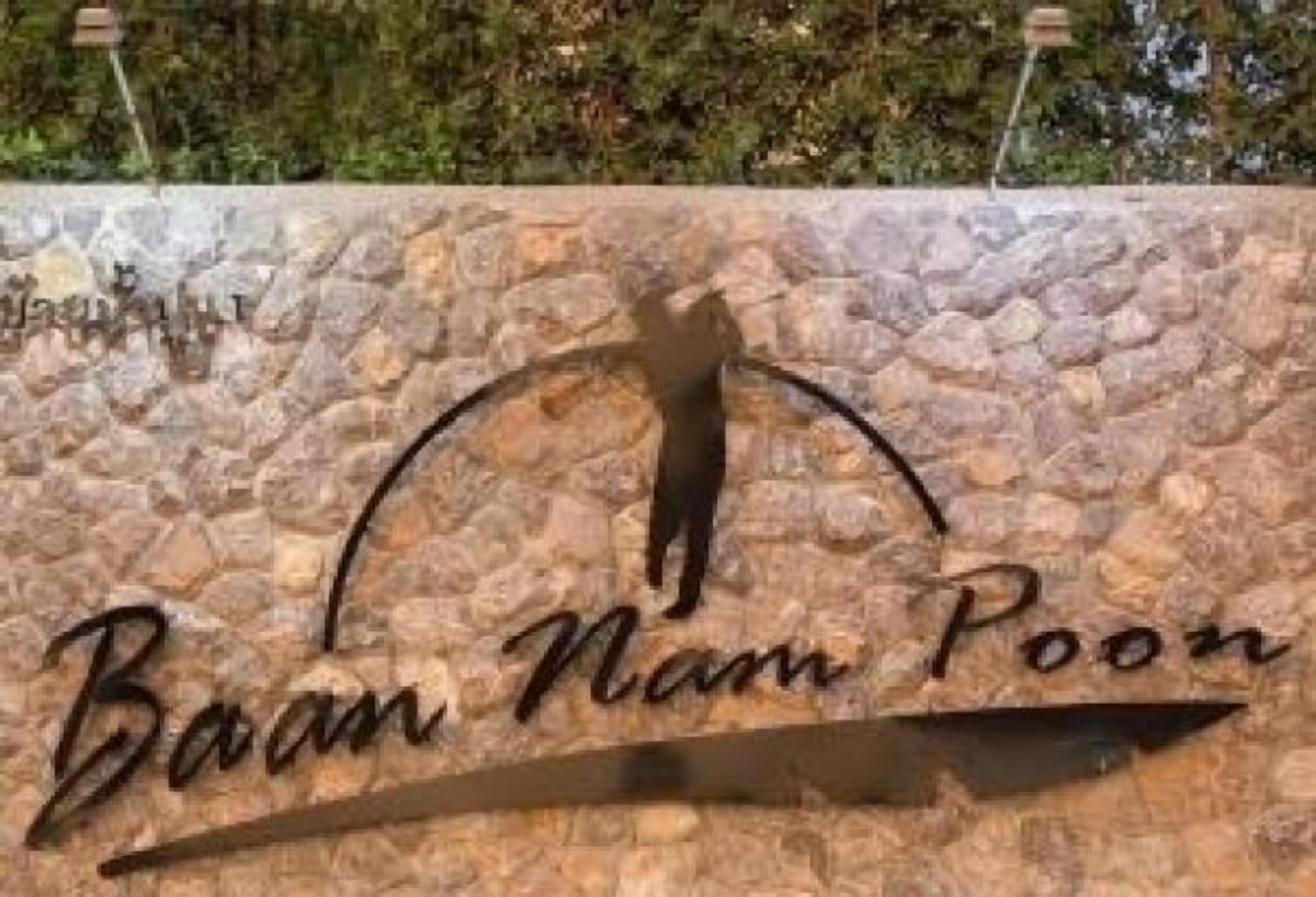 Uma parede de pedra com o nome 'Baan Nam Poon' gravado.