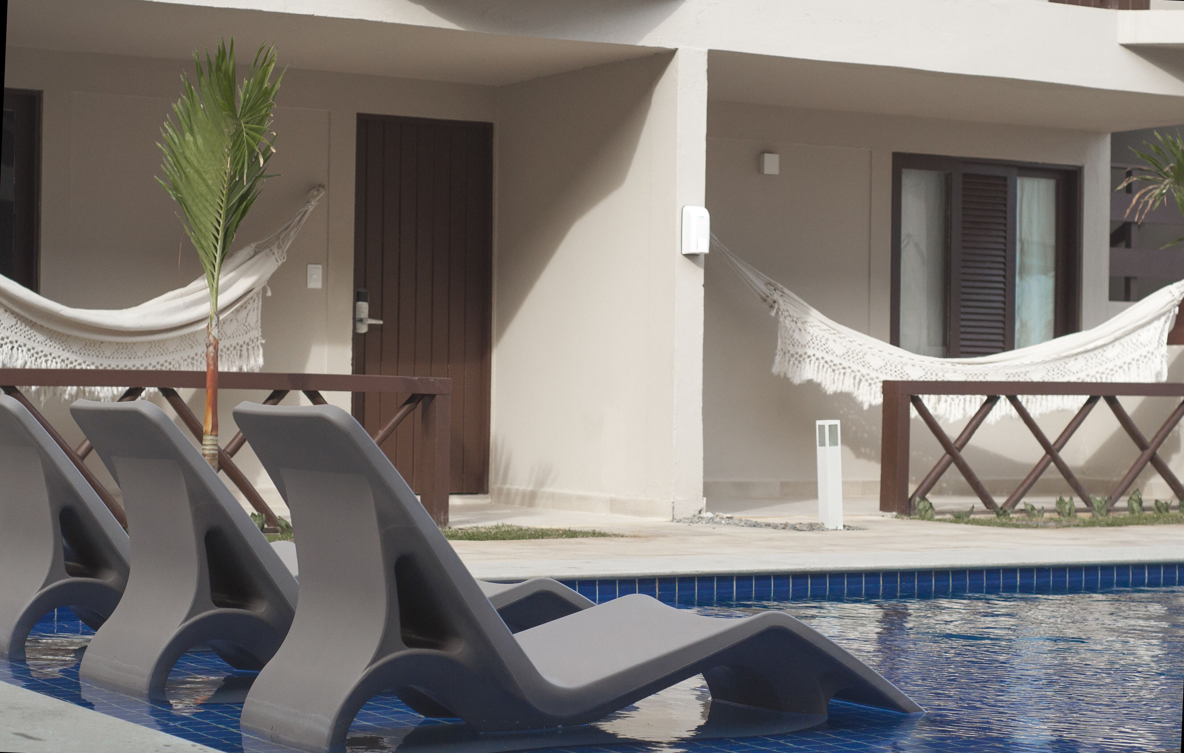 Área da piscina com espreguiçadeiras e rede.