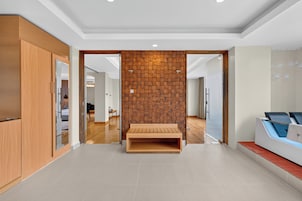 Decoração moderna com um banco de madeira, balcão de recepção e vista para um quarto com cama e escrivaninha.