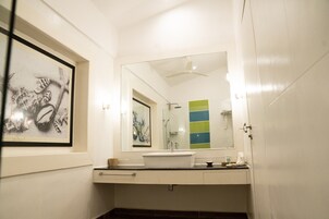 Um banheiro com pia branca, espelho e um quadro pendurado na parede.