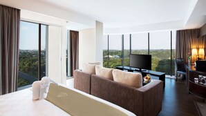Quarto de hotel moderno com uma cama grande, sofá, TV e varanda com vista para a cidade.