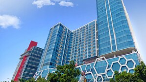 Um edifício alto com fachada de vidro moderna e um elemento vertical vermelho característico.