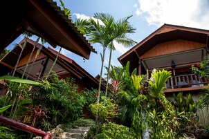 Um resort tropical com estruturas de madeira, vegetação exuberante e céu claro.
