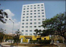 Um hotel com vários andares, fachada plana, entrada amarela e uma placa com a inscrição 'lemon tree hotel'.