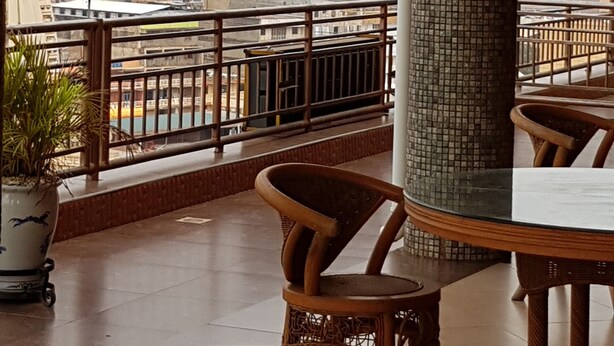 Terraço com móveis de vime e vista para a paisagem urbana.