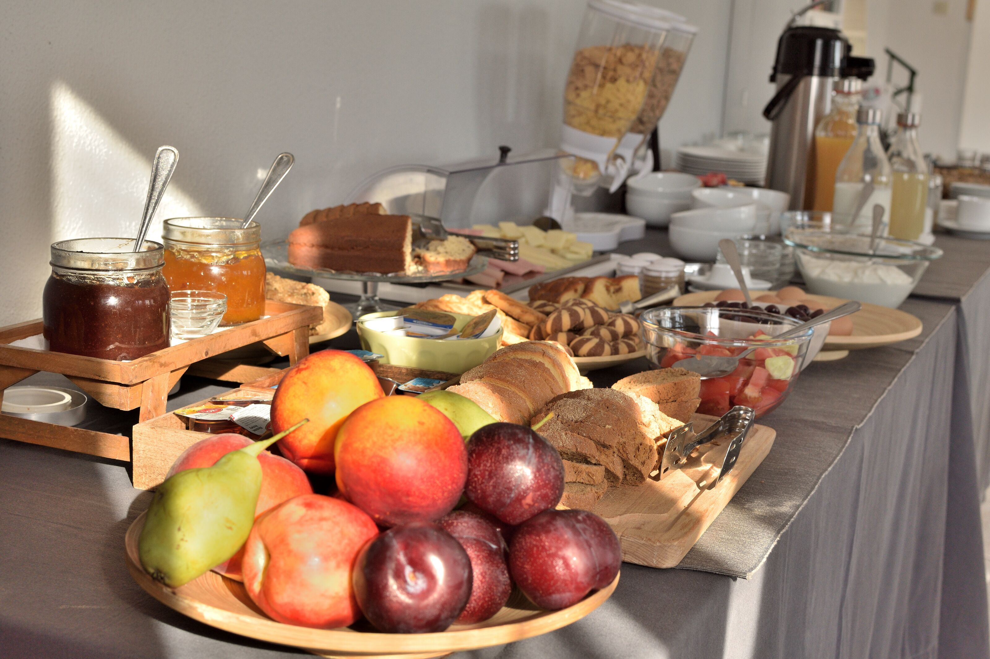Um buffet de café da manhã com diversas frutas, doces e bebidas.