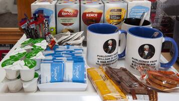 Exposição de produtos de café, incluindo marcas de café em embalagem, cápsulas e canecas com figuras históricas.