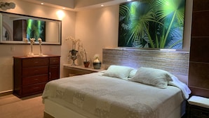 Um quarto com uma cama, cômoda, espelho e luminária fixada na parede.