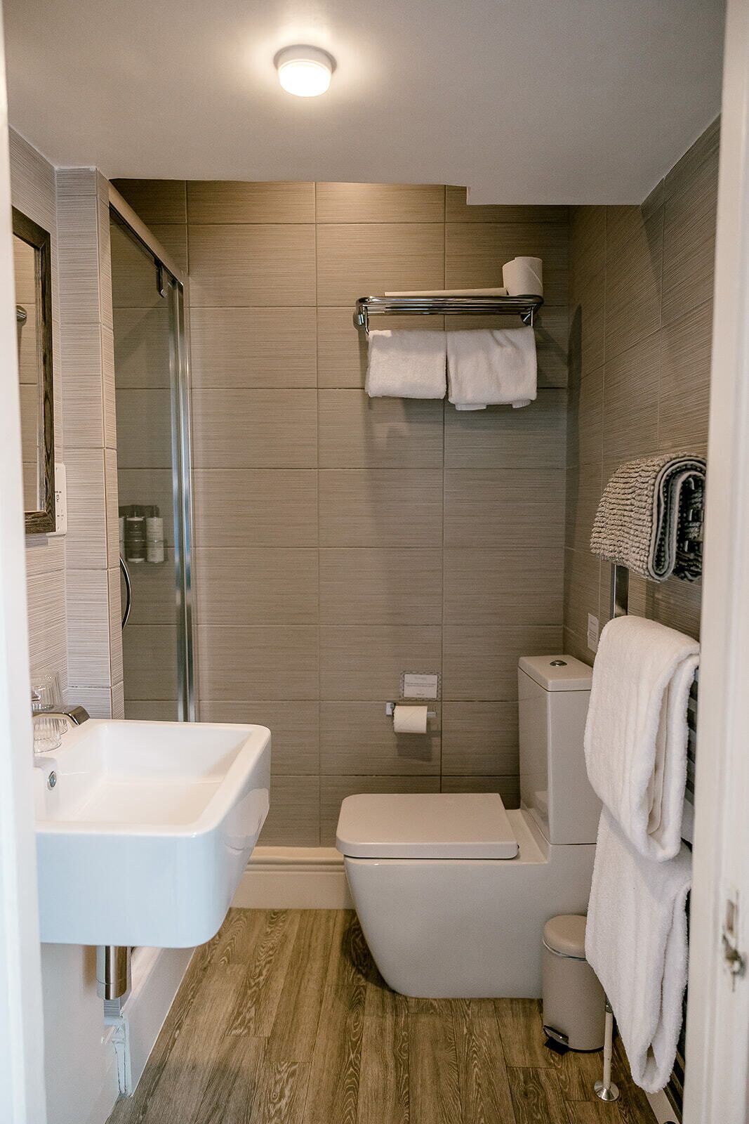 Uma casa de banho moderna com chuveiro, sanita e lavatório.