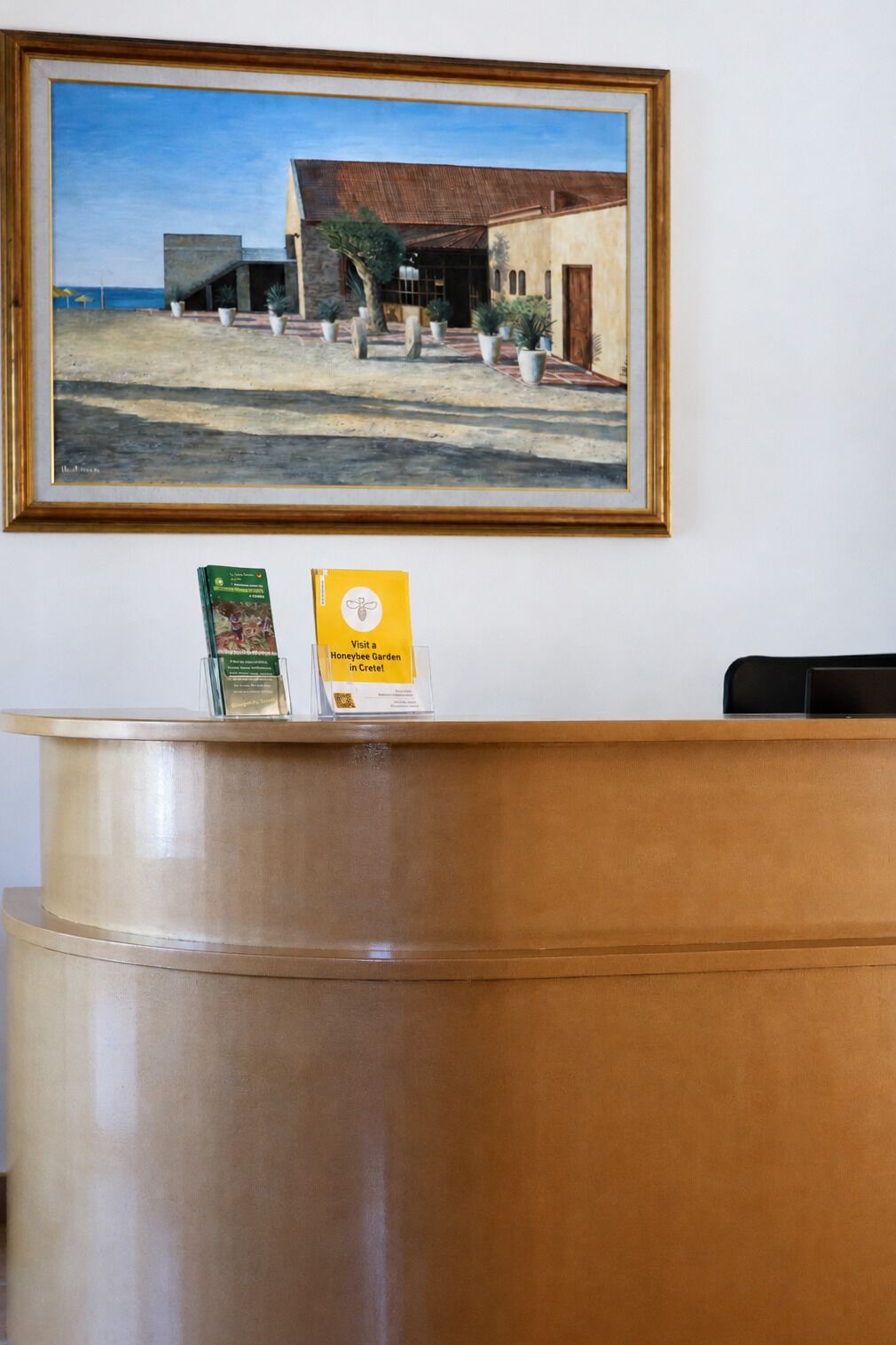 Uma receção com um quadro emoldurado acima, um letreiro amarelo e dois livros no balcão.