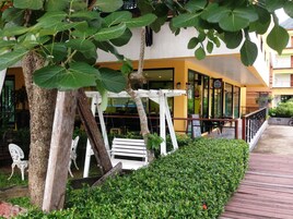 Um edifício com fachada amarela e branca, um deque de madeira e um balanço branco.