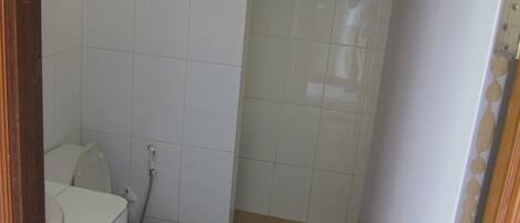 Uma casa de banho pequena com sanita, chuveiro e lavatório.