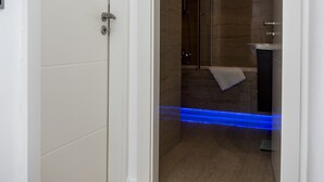 Uma casa de banho moderna com chuveiro, lavatório e toalha pendurada na parede.