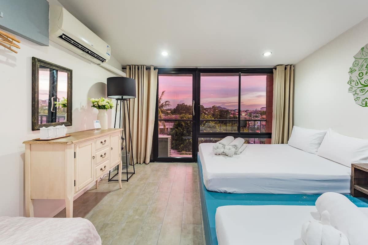 Quarto de hotel com uma janela grande, uma cama, uma escrivaninha e um armário.