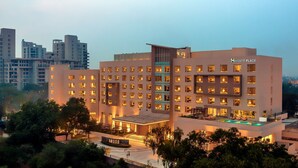 Um hotel com vários andares e design moderno, com área de piscina no terraço e fachada bem iluminada.