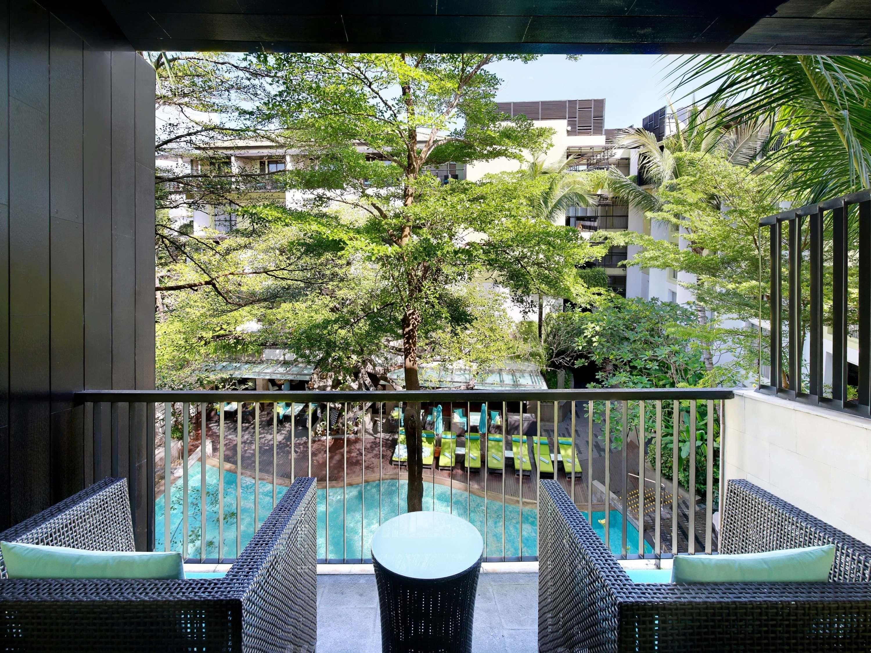 Varanda com móveis de vime e vista para uma piscina.