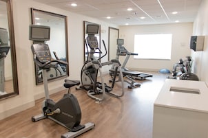 Centro de fitness com esteiras, elípticos e um banco de musculação.