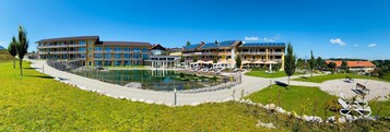 Um hotel com vários andares, piscina ao ar livre e espreguiçadeiras.