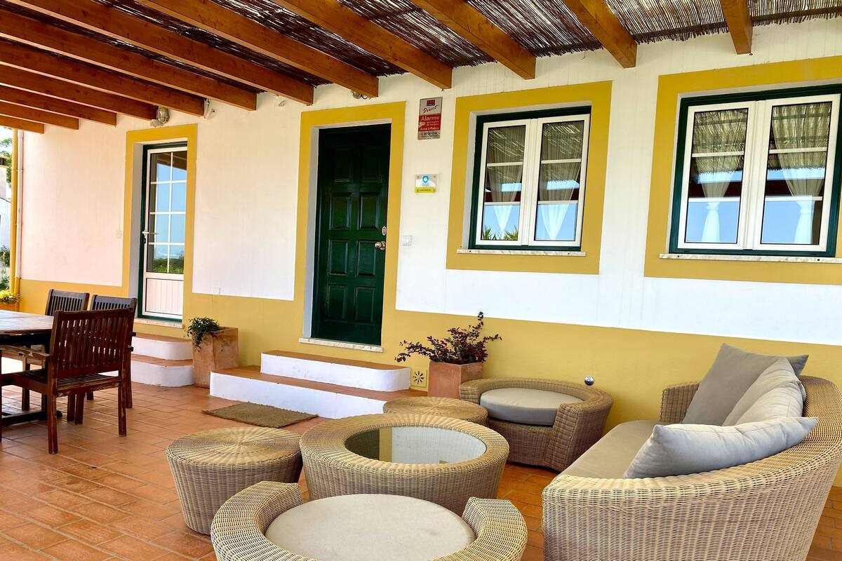 Uma área de estar acolhedora ao ar livre, com mobiliário de vime e uma mesa de jantar.
