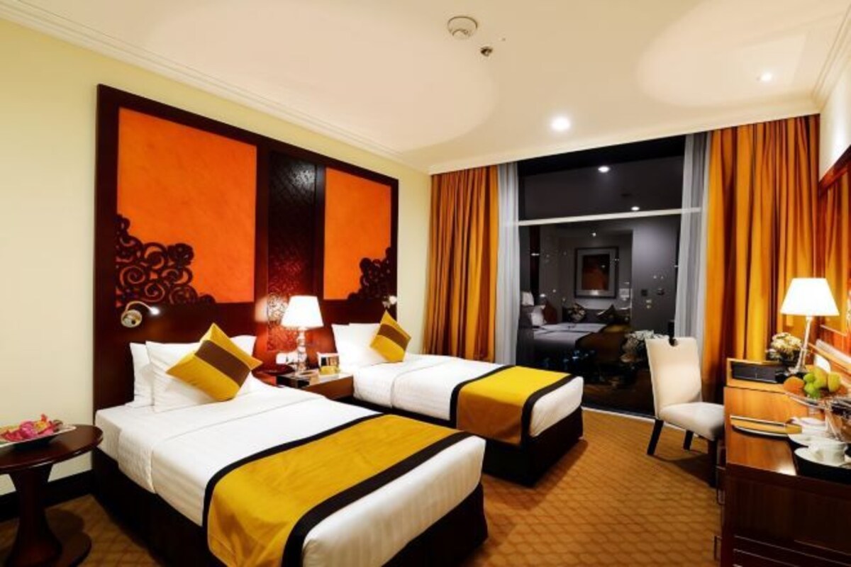 Quarto de hotel com duas camas, uma escrivaninha, uma cadeira e vista para a cidade.
