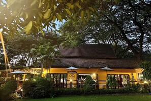Um restaurante com mesas ao ar livre, telhado de azulejos e uma placa indicando que é um café.