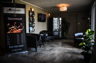Interior de pub com área de recepção, assentos, máquina de vendas automática e televisão.