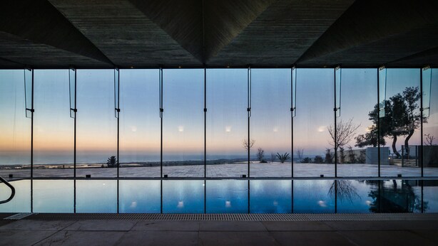 Piscina com vista para o mar e um pôr do sol.