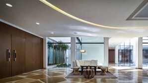 Um lobby moderno com parede de vidro, área de estar e um armário de madeira.