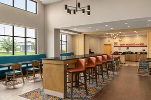 Um lobby moderno de hotel com área de bar, assentos e vista para o exterior.