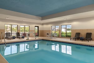 Área de piscina com espreguiçadeiras e mesa, janelas amplas e vista desimpedida para o exterior.