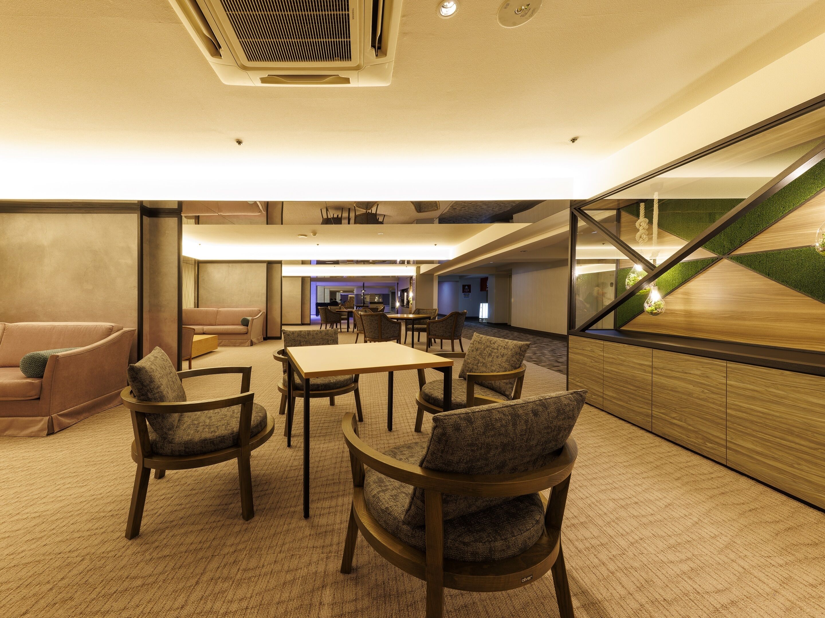 Um saguão de hotel moderno com área de estar, uma escadaria e vista do interior.