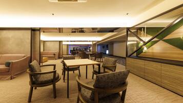 Um saguão de hotel moderno com área de estar, uma escadaria e vista do interior.