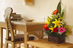 Uma mesa de jantar de madeira com uma cadeira, uma pequena pilha de livros e um vaso de flores.