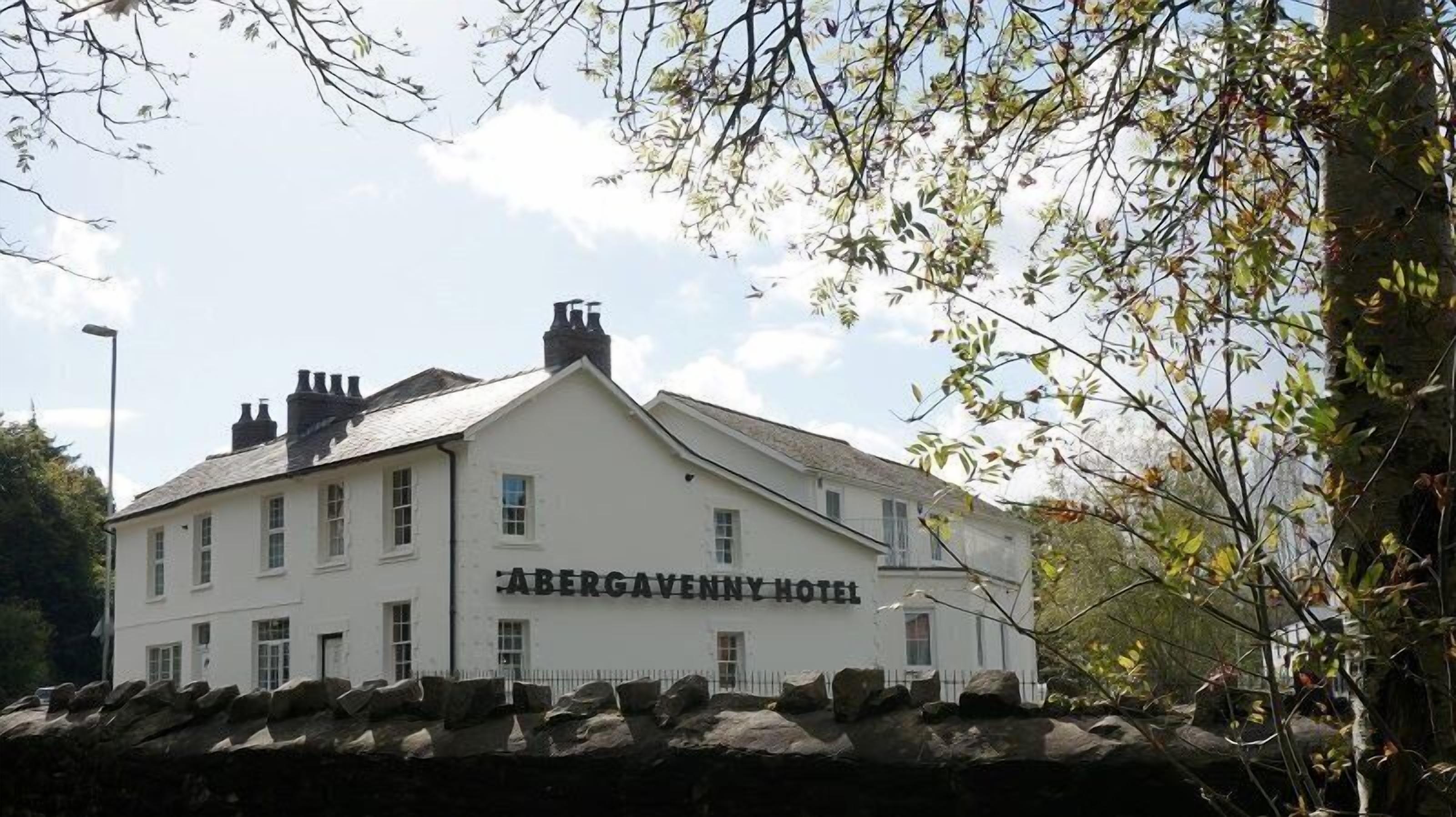 Um edifício branco com a placa 'ABERGAVENNY HOTEL' na fachada.