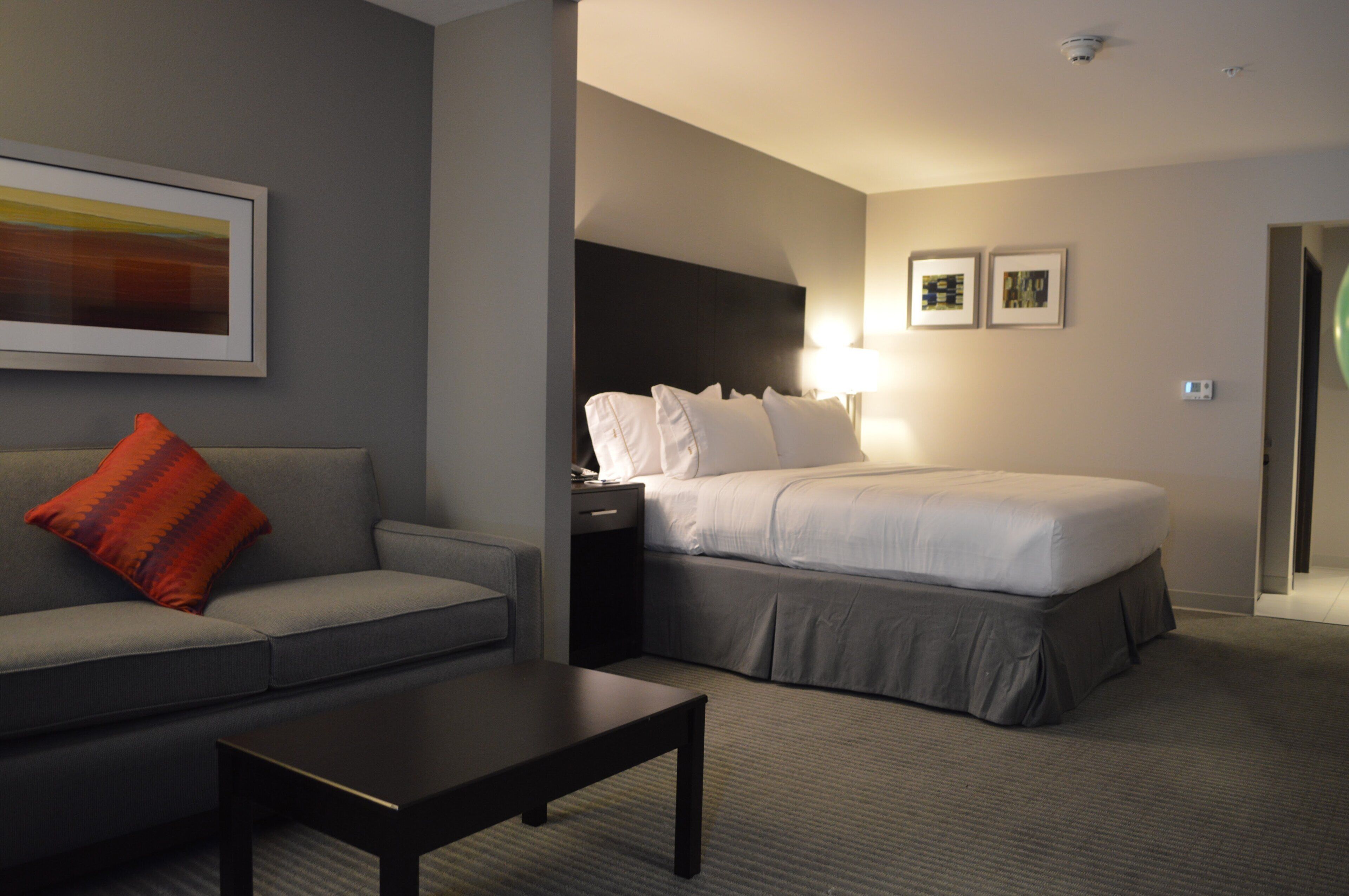 Quarto de hotel com uma cama, um sofá, uma mesa de centro e uma mesinha de cabeceira.