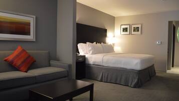 Quarto de hotel com uma cama, um sofá, uma mesa de centro e uma mesinha de cabeceira.