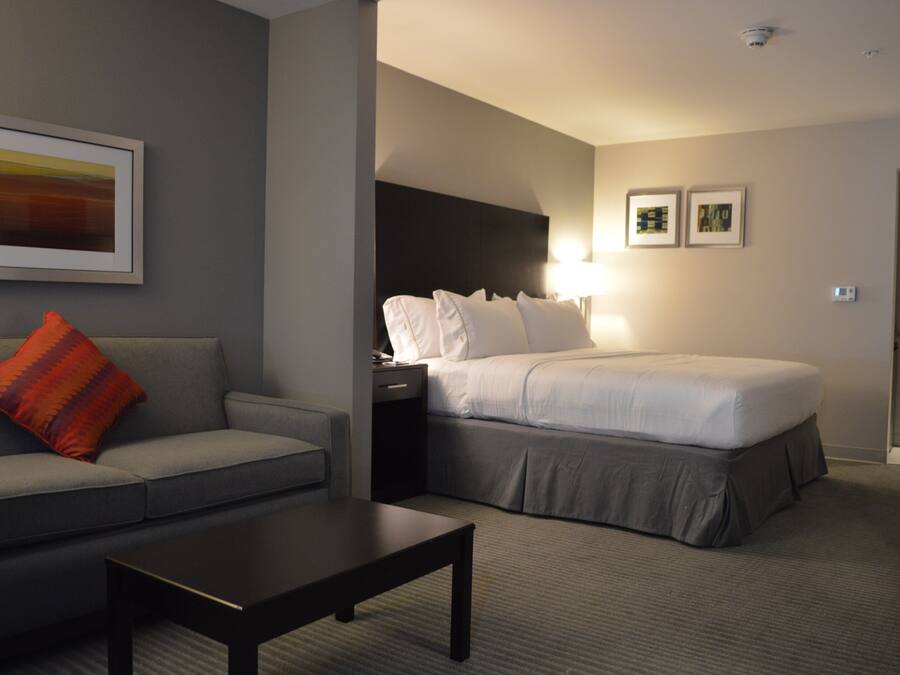 Quarto de hotel com uma cama, um sofá, uma mesa de centro e uma mesinha de cabeceira.